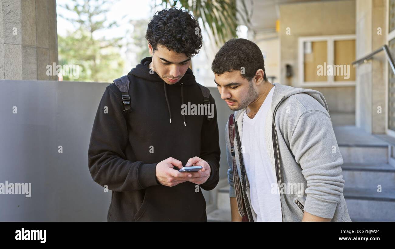 Two hispanic men casually dressed, standing on a city street, focused ...