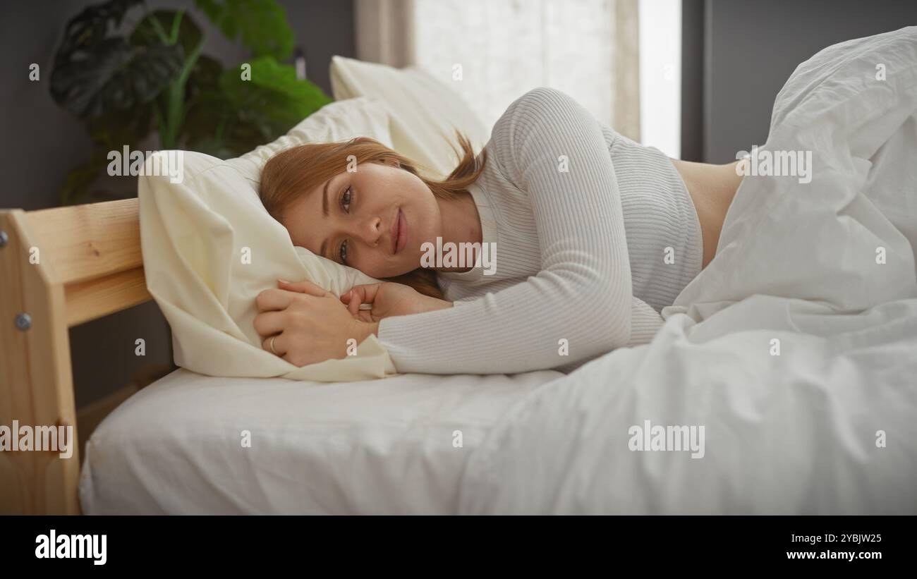 A beautiful young caucasian woman with red hair smiling as she relaxes ...