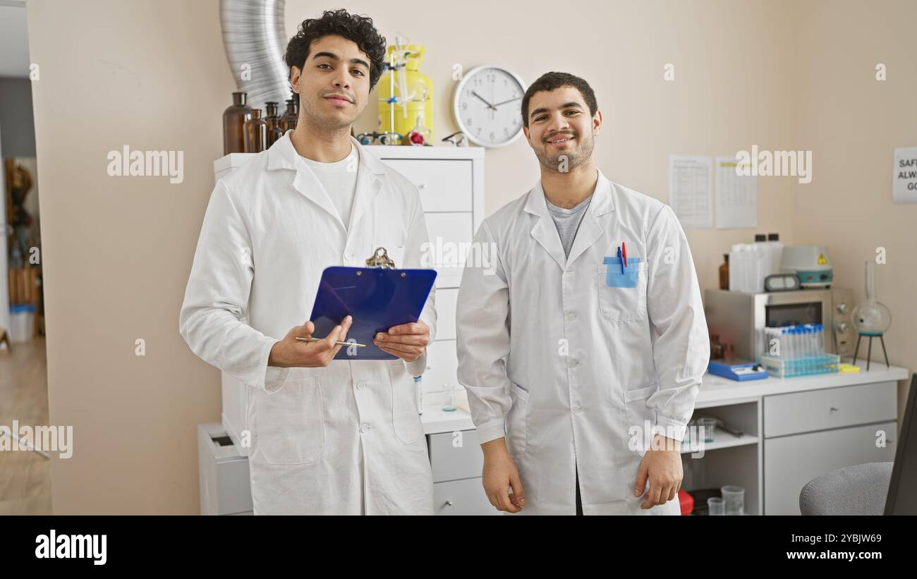 Two men in a laboratory wearing lab coats, one holding a clipboard ...