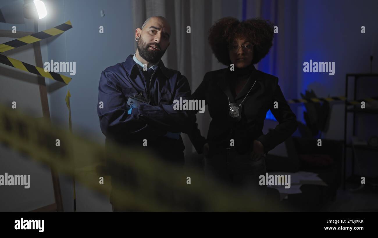A man and a woman, both with badges, stand with crossed arms at an ...