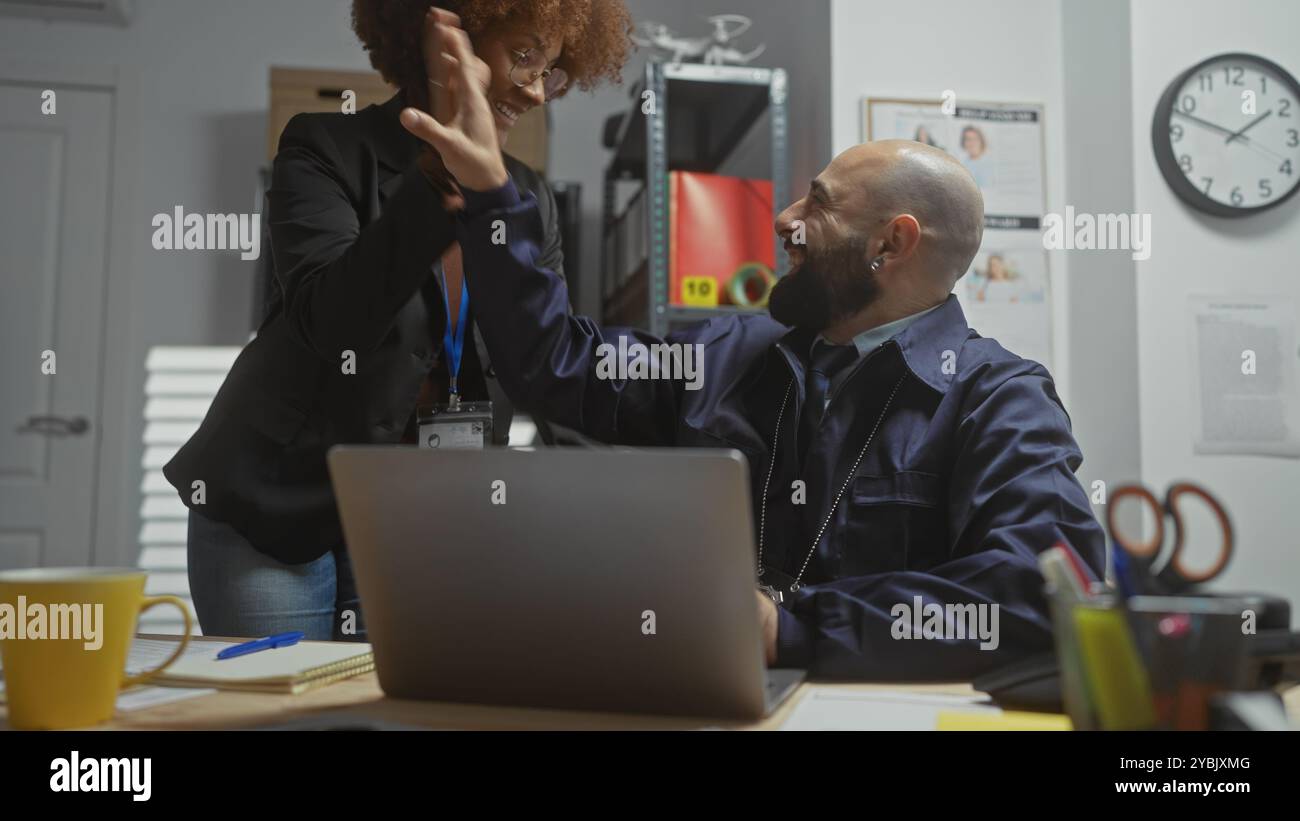 A woman and a man celebrate success with a high-five in a modern police ...