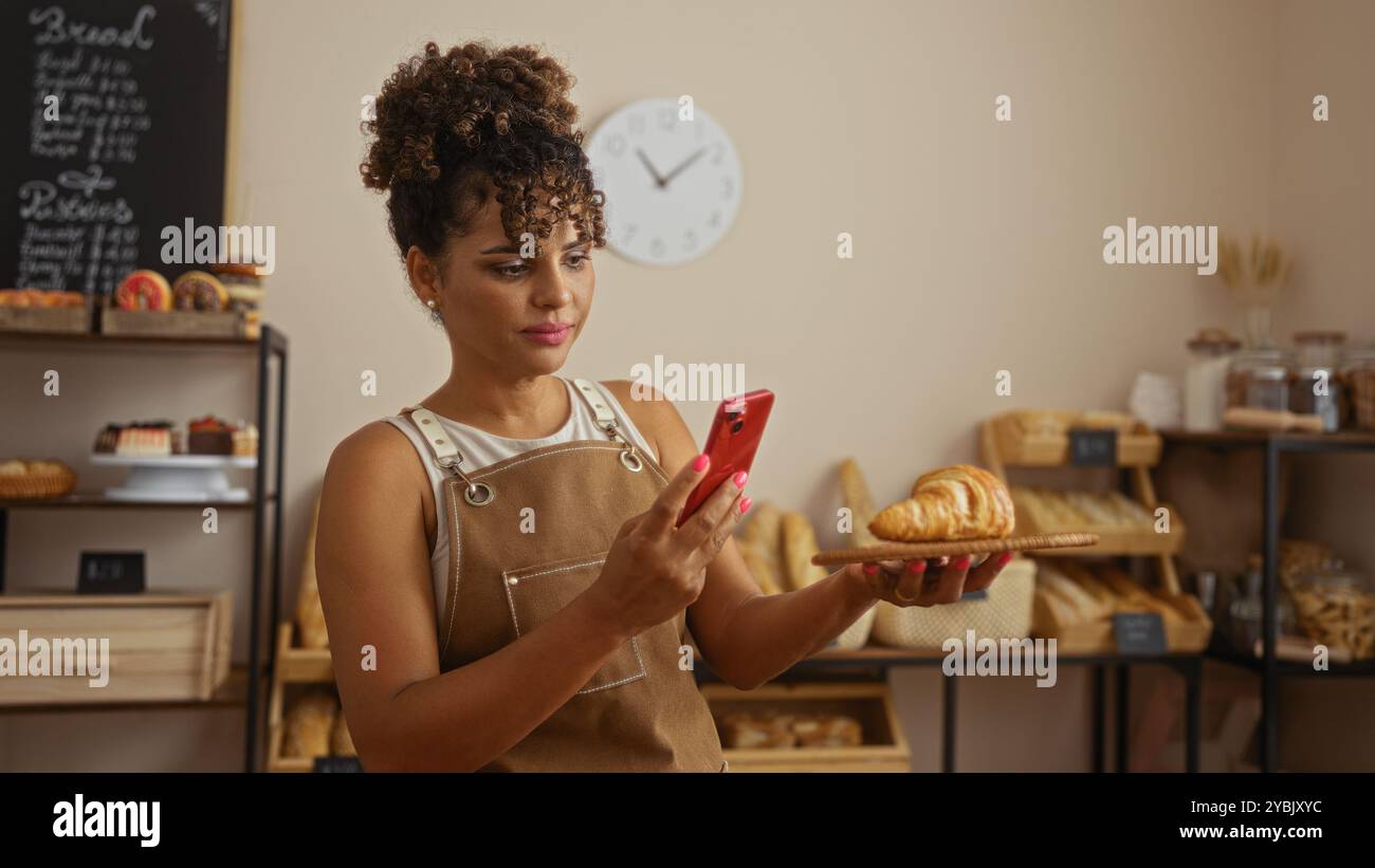 Young woman in a bakery taking a photo of a croissant with her mobile ...
