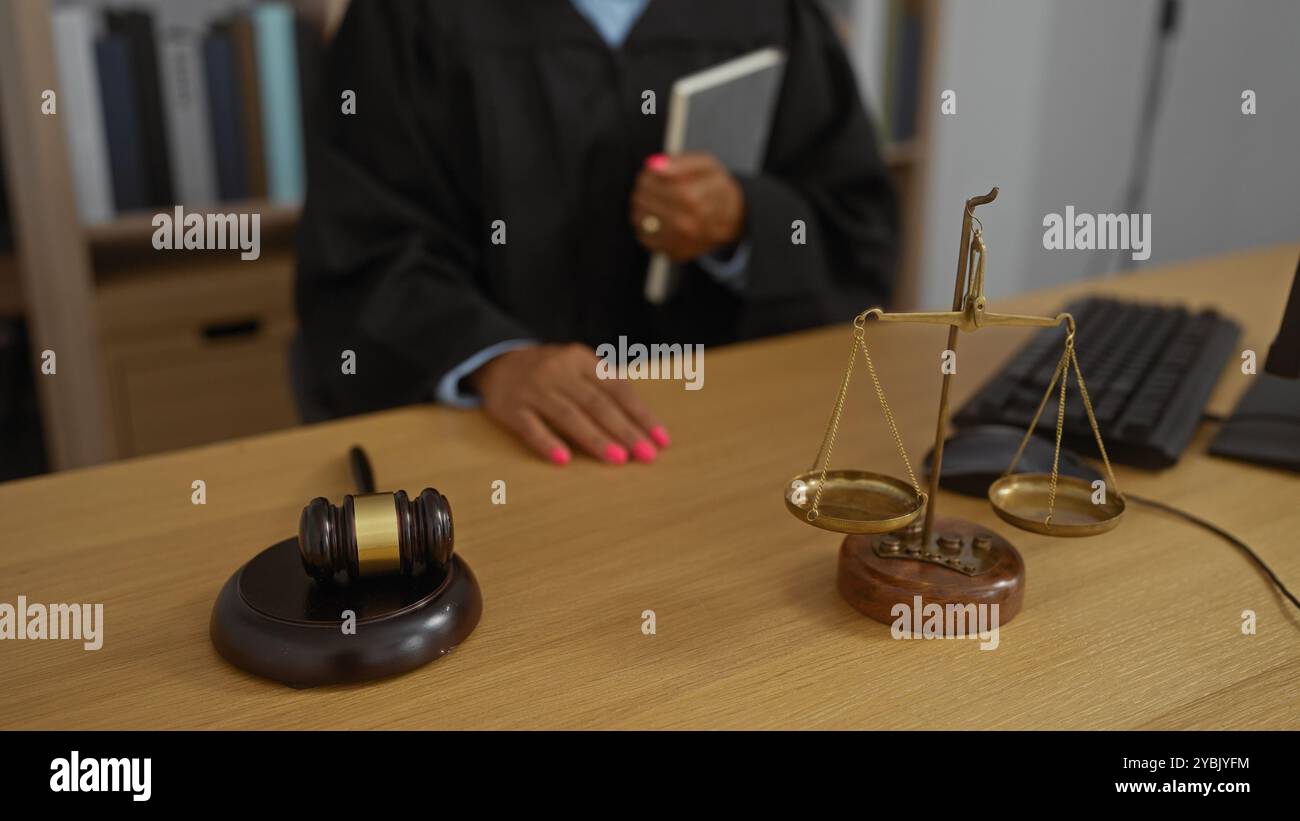 Female judge with book standing behind desk with gavel and scales in ...