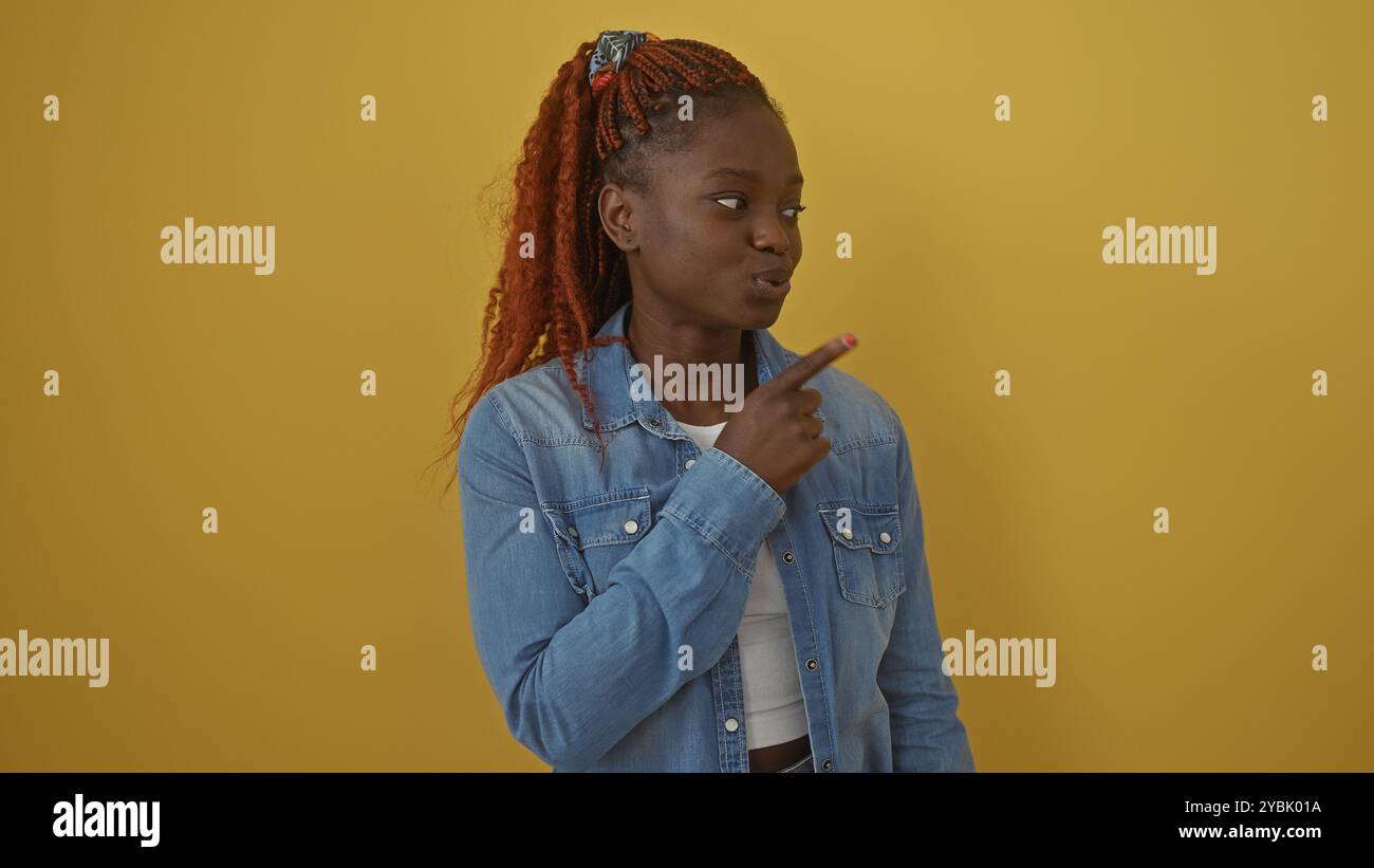 A thoughtful young adult african woman in denim gestures on a vibrant ...