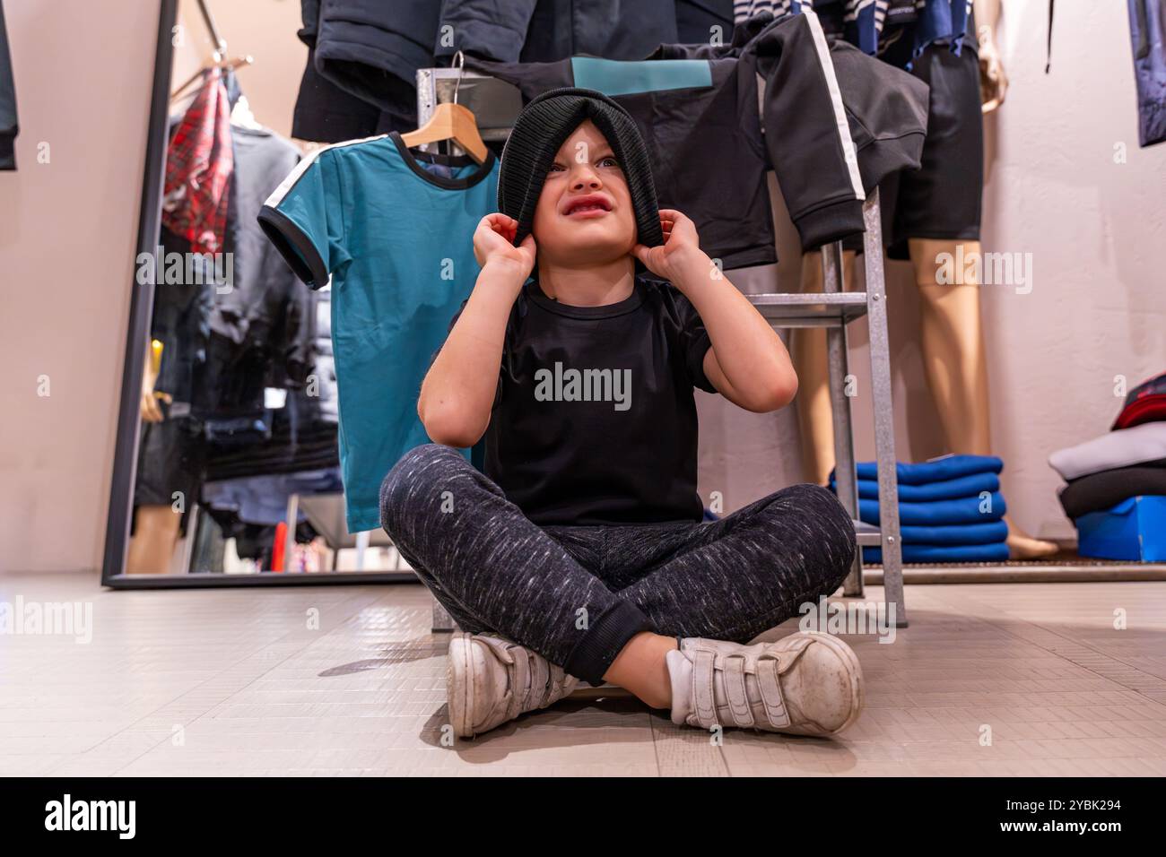 young expressive child having fun posing as a model in a clothing store ...
