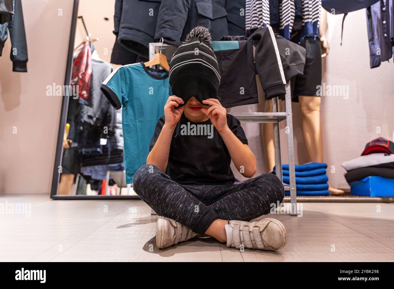 young expressive child having fun posing as a model in a clothing store ...