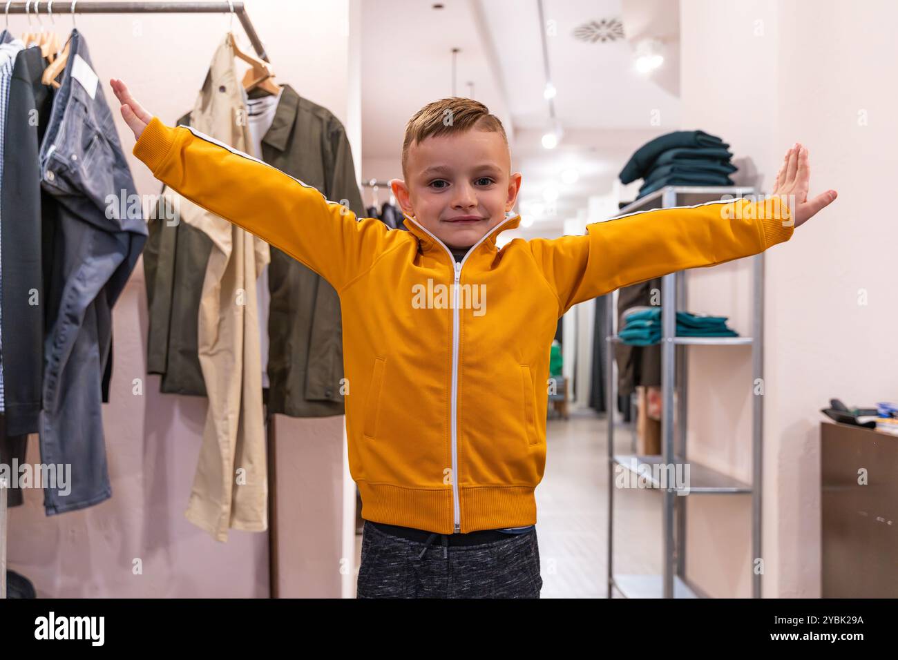 young expressive child having fun posing as a model in a clothing store ...