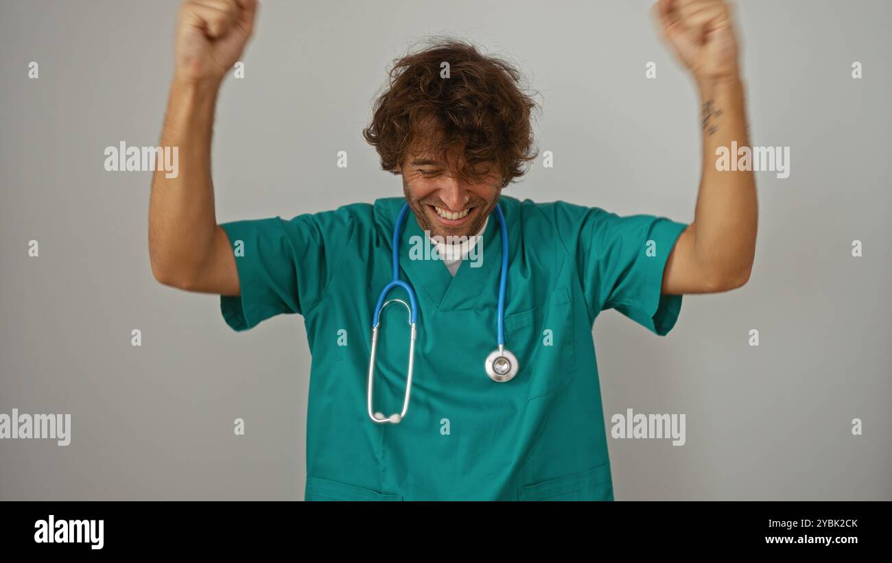 Young man celebrating in medical scrubs with stethoscope over isolated ...