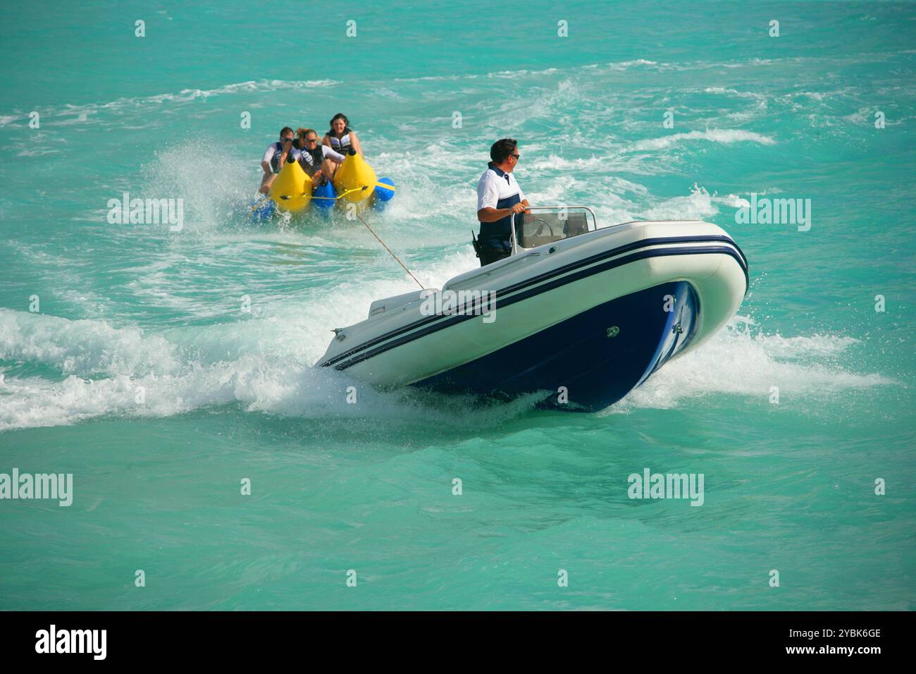 People having fun on an inflatable banana boat being towed at speed ...