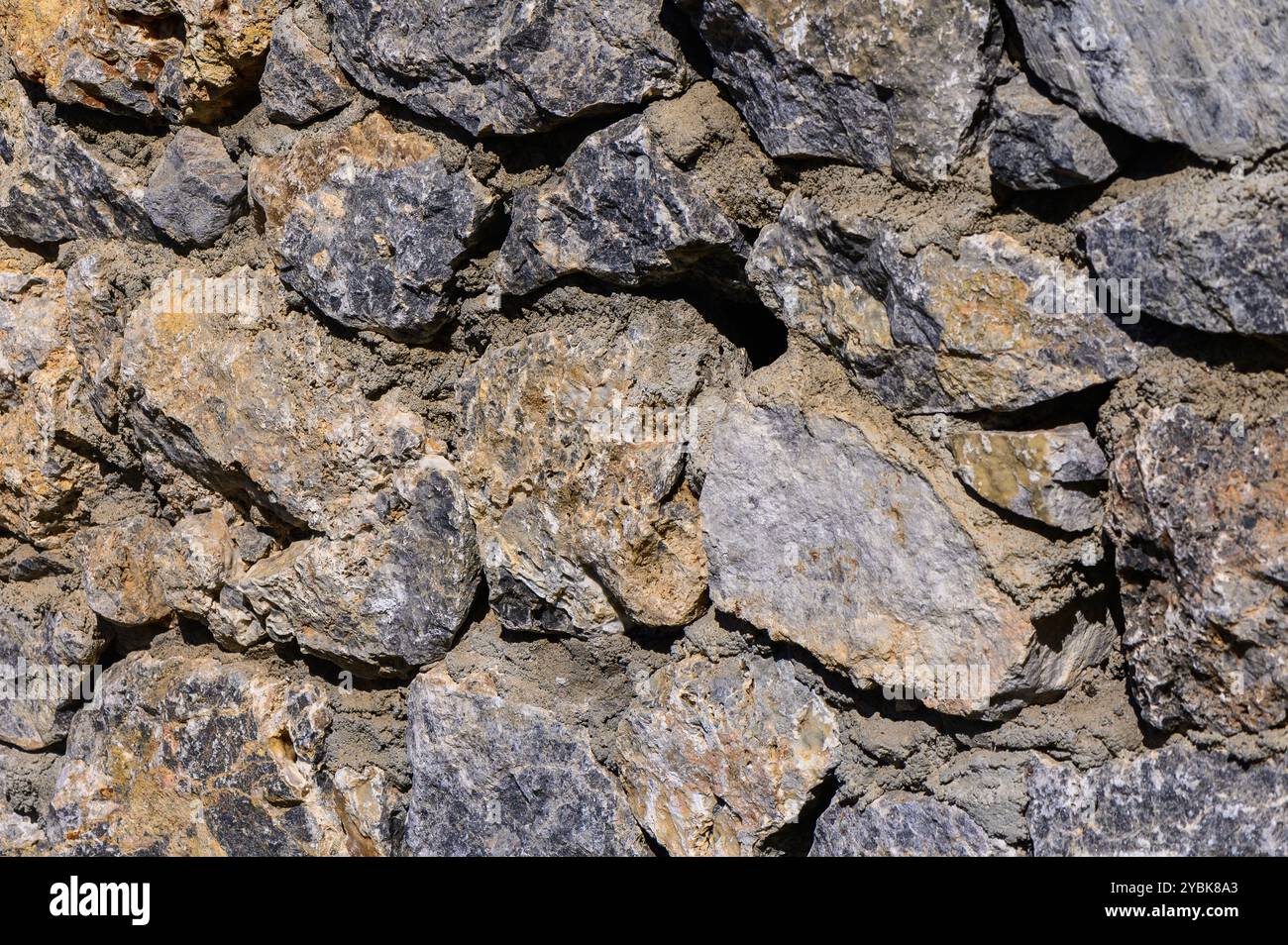 Rugged stones of various sizes and colors are arranged into a solid ...