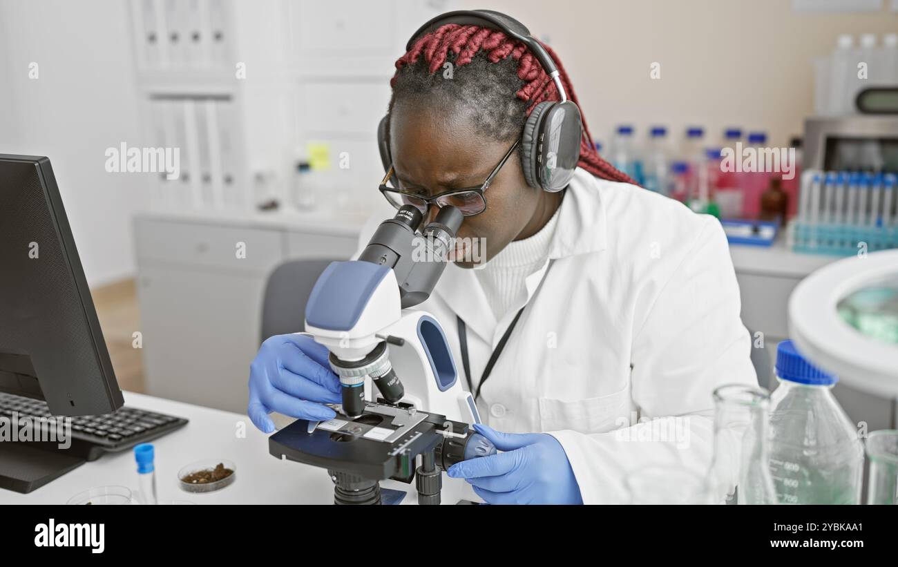 African american scientist with braids using microscope in laboratory ...