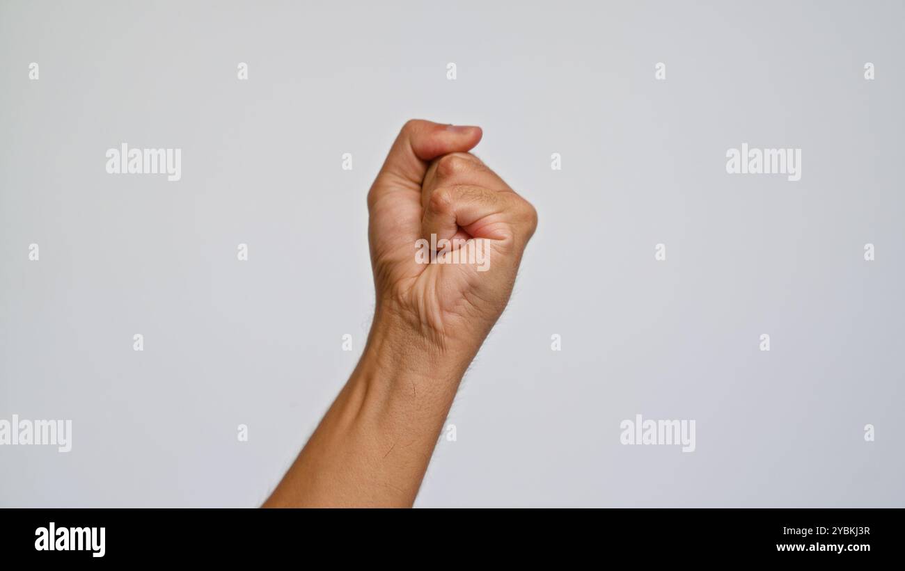 Man raising clenched hand in front of plain white background ...