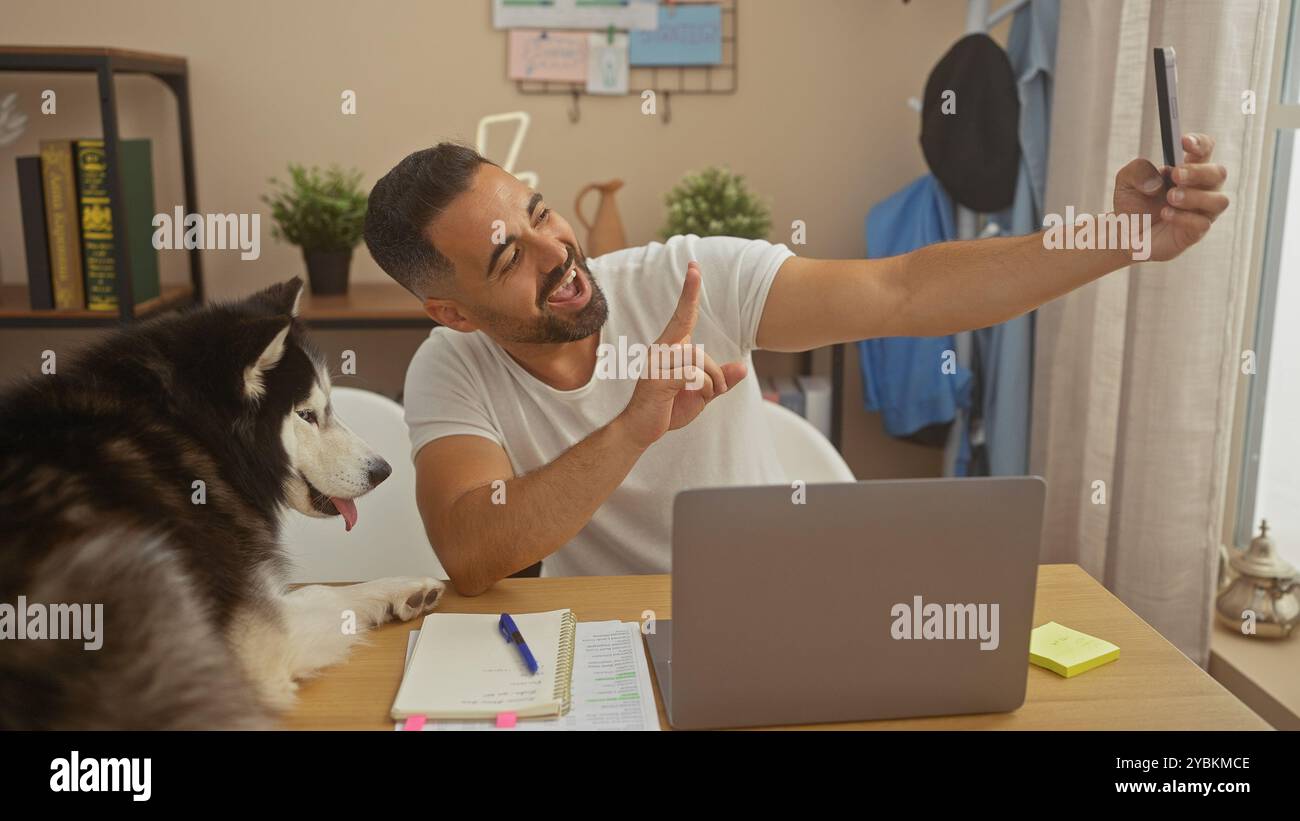 A cheerful hispanic man takes a selfie with his husky dog in a cozy ...