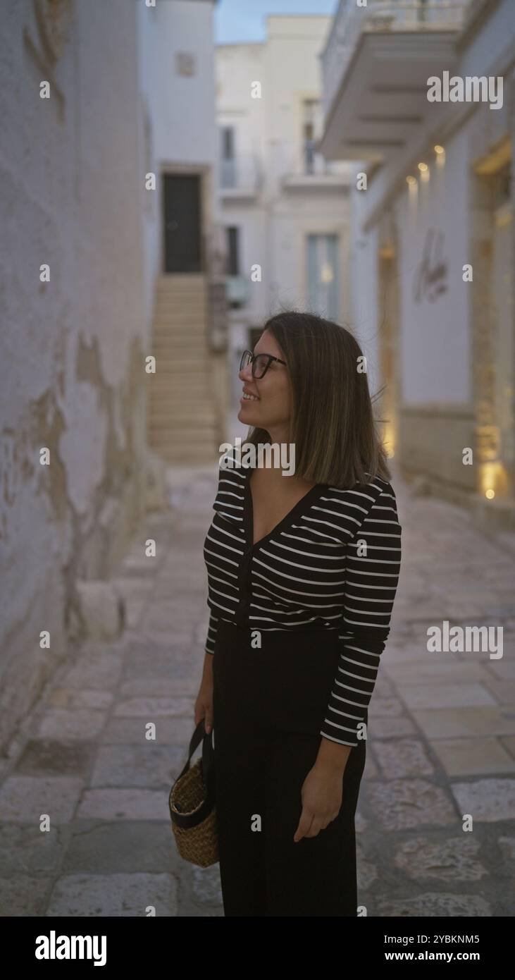 A beautiful young hispanic woman walks through the charming streets of ...