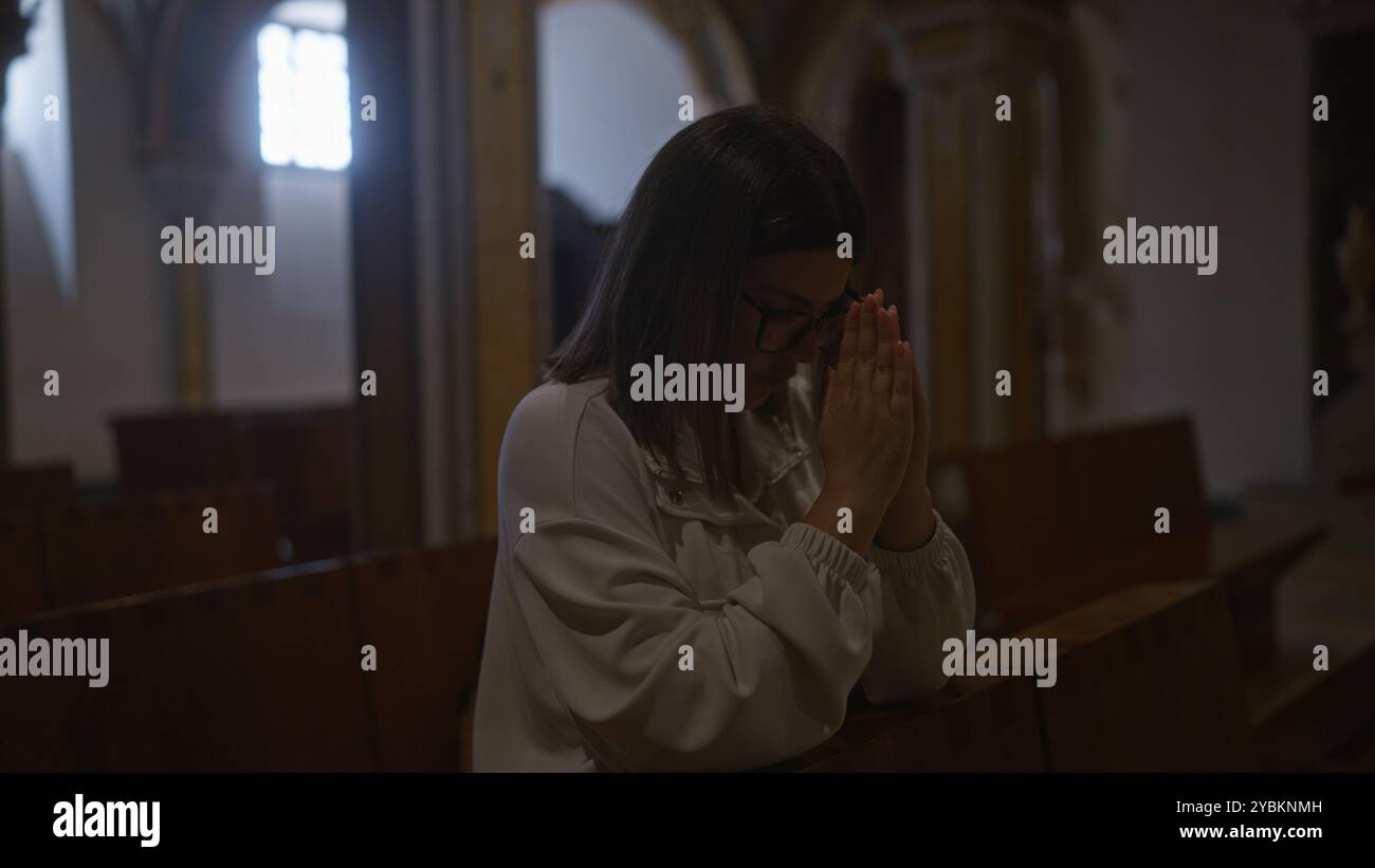 A young hispanic woman is praying solemnly inside a beautiful christian ...