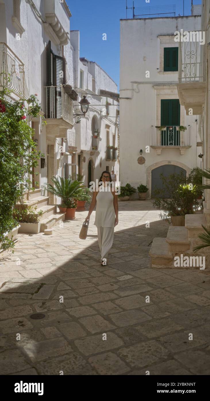 A young hispanic woman walks down a picturesque street in the old town ...