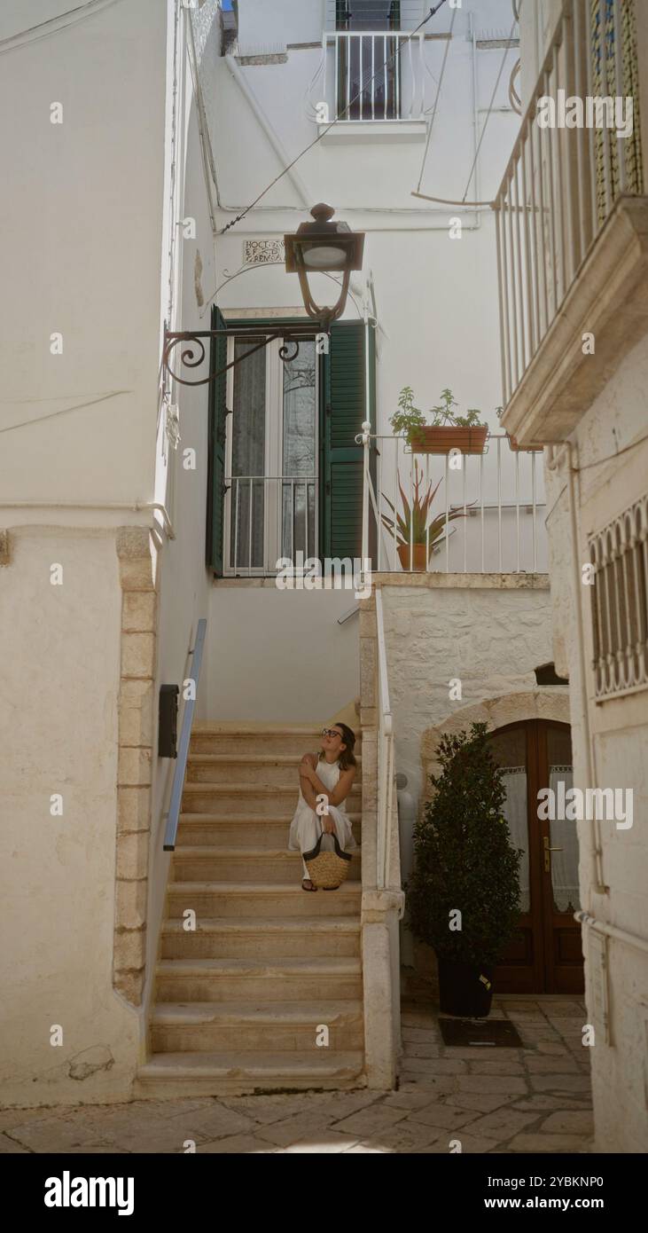 A young hispanic woman sitting on stone steps in the charming old town ...