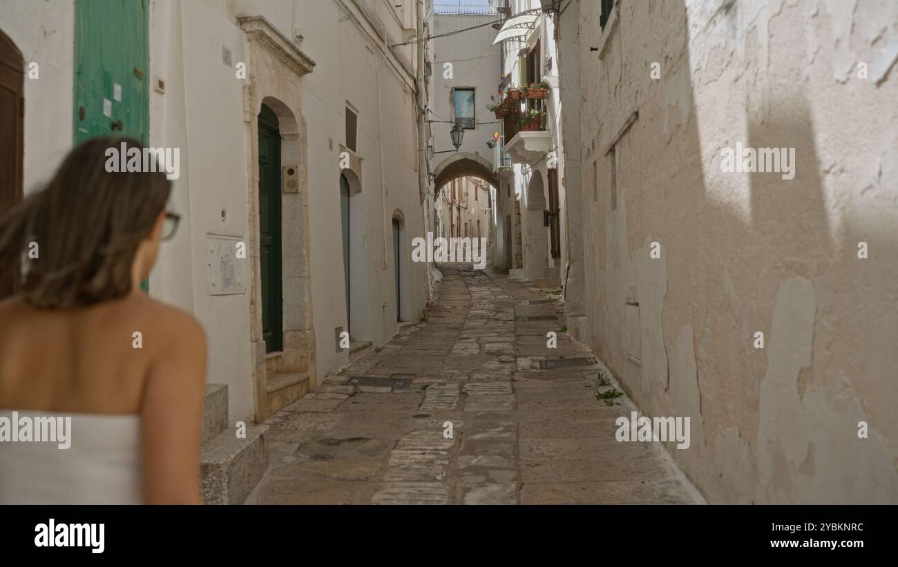 A young hispanic woman explores the charming narrow streets of ostuni's ...