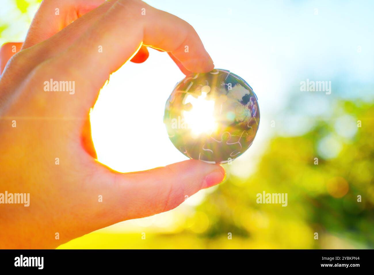 Concept of renewable energy with a hand holding a globe-shaped puzzle ...