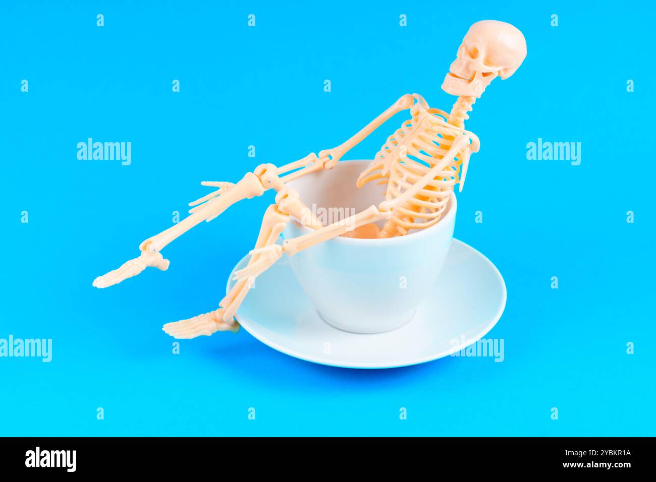 Whimsical skeleton sitting comfortably inside a white cup against a ...
