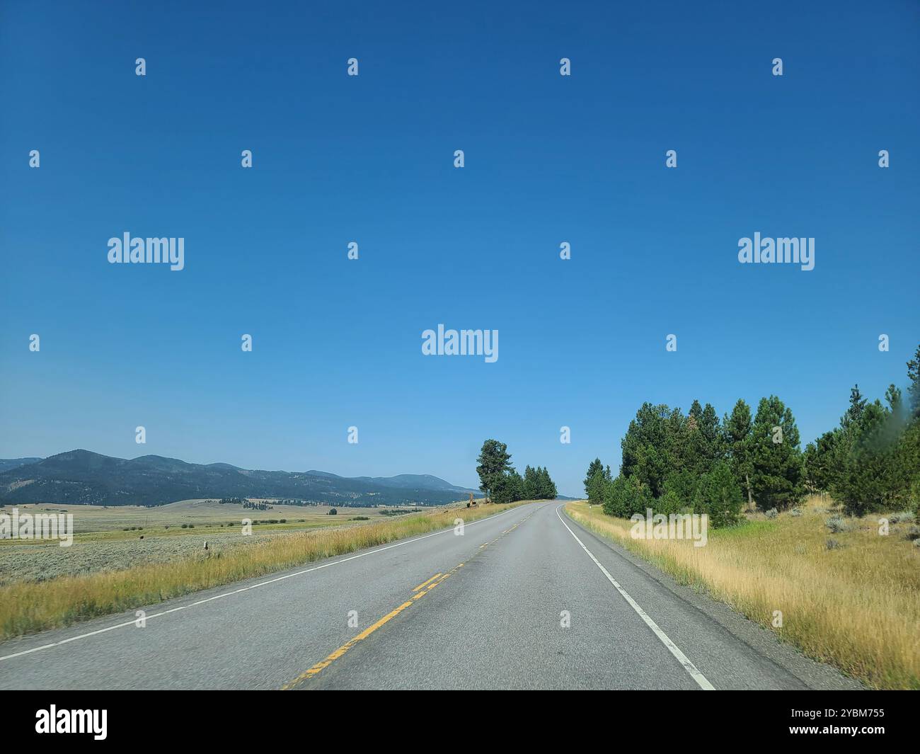 A long, straight road stretches through a vast, open landscape with ...