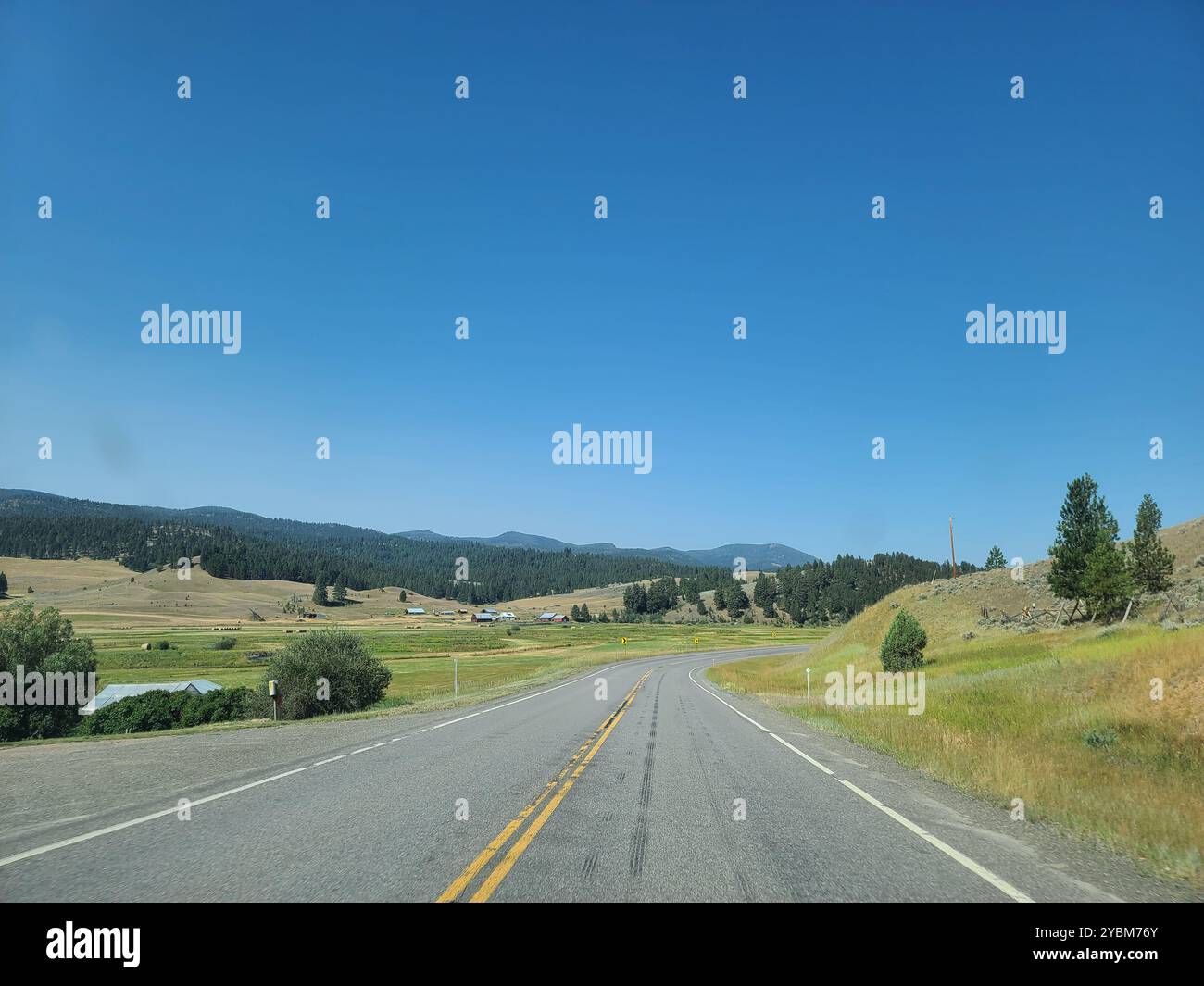 A long, straight road stretches through a vast, open landscape with ...