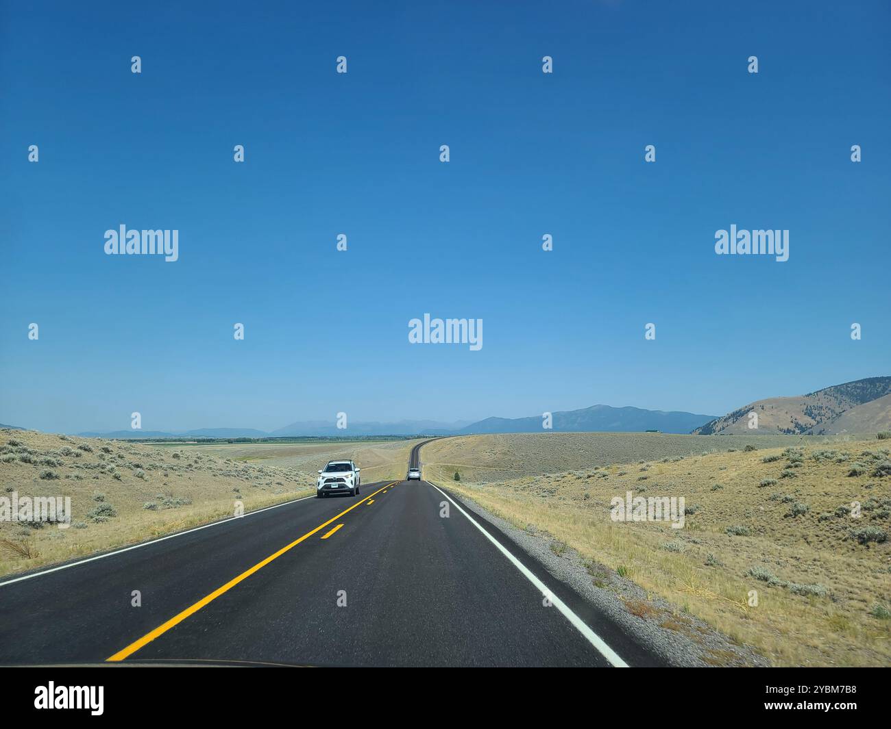 A long, straight road stretches through a vast, open landscape with ...