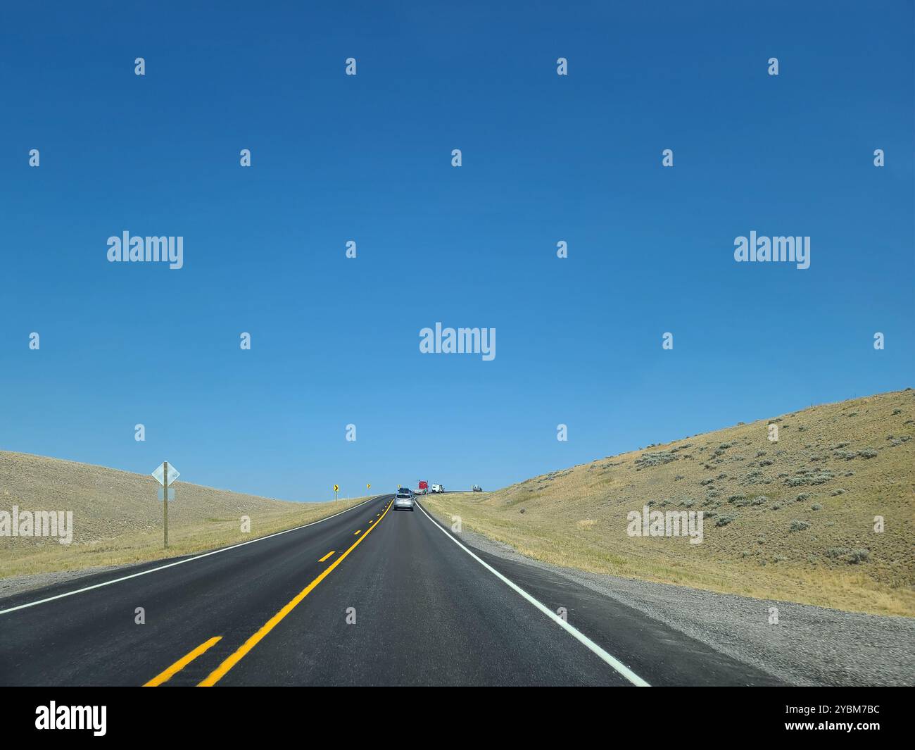 A long, straight road stretches through a vast, open landscape with ...