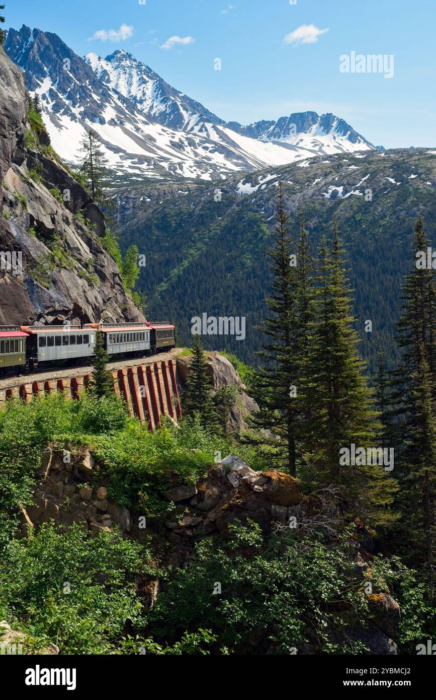 A scenic passenger train rounding a curve high in the mountains above Skagway, Alaska Stock ...