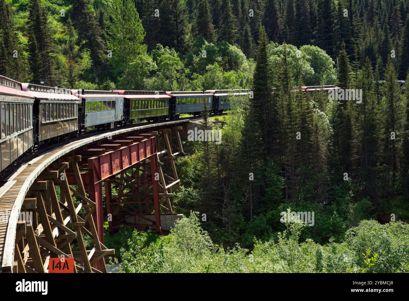 A passenger excursion train rounds a curved bridge over a ravine near ...