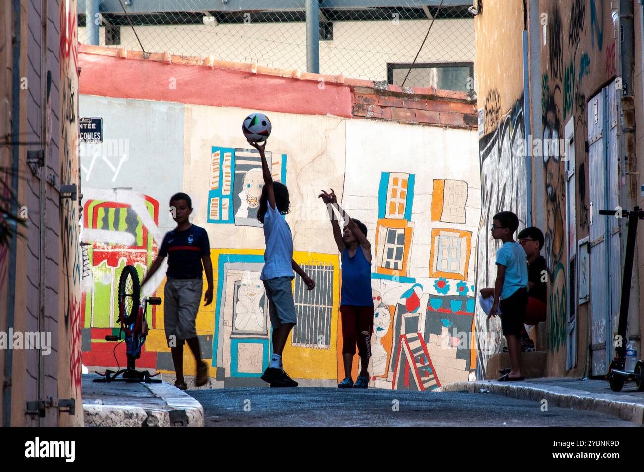 Children play ball in an alley with street art in the Le Panier ...