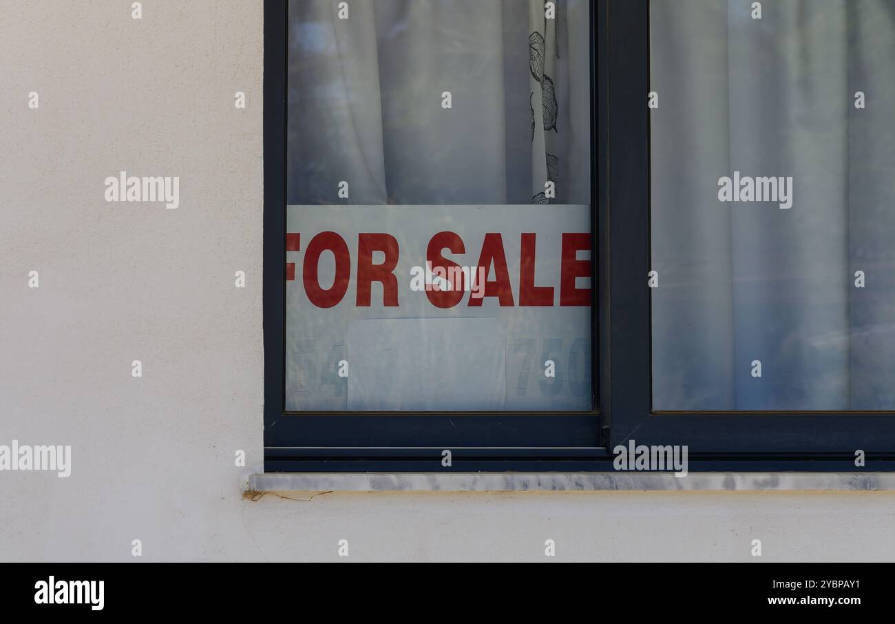 A bold red 'For Sale' sign prominently displayed in a window suggests ...