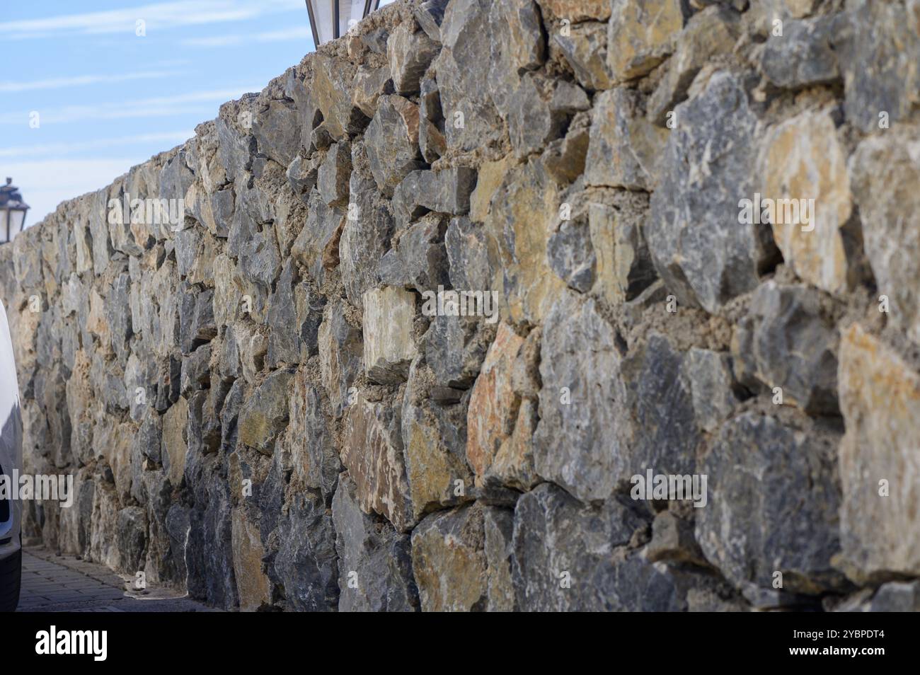 The sturdy stone wall proudly lines the pathway, blending seamlessly ...