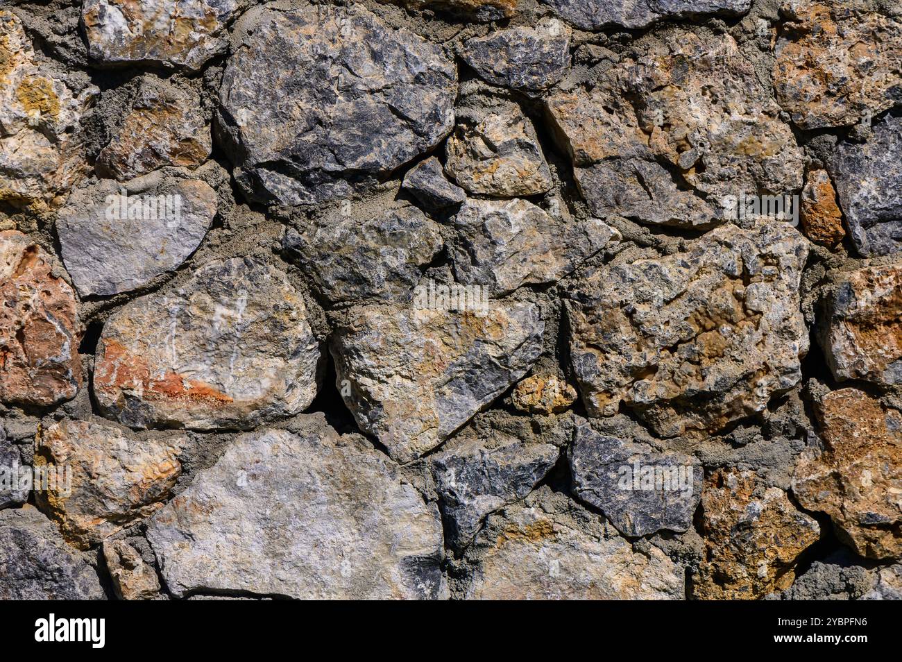 A rugged wall formed by an assortment of rocks in different shapes and ...