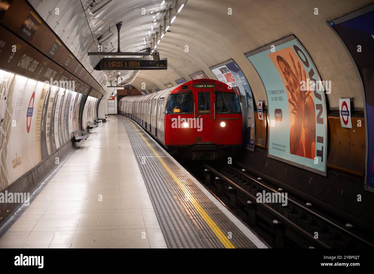Red London Underground Tube train arriving at station, empty platform ...