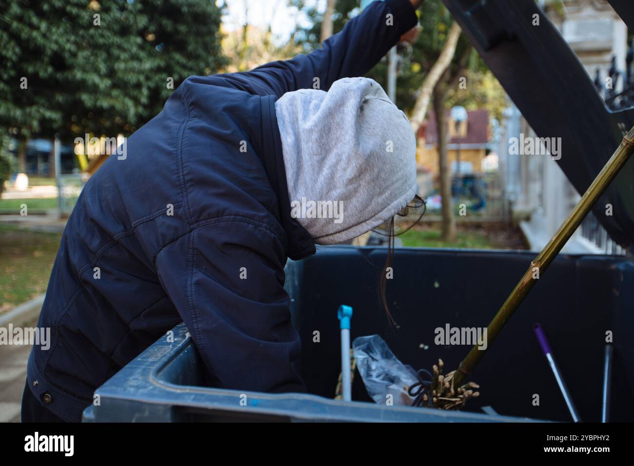 Homeless man looking into trash box in search for food on church ...