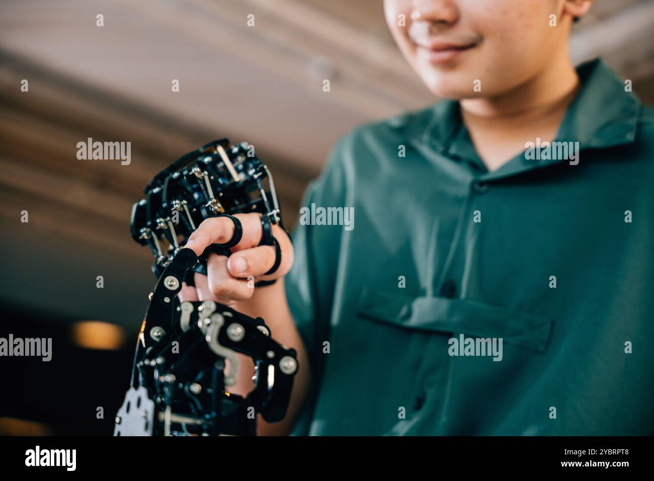 In a technical college setting a teenage boy tests a robot hand and arm ...