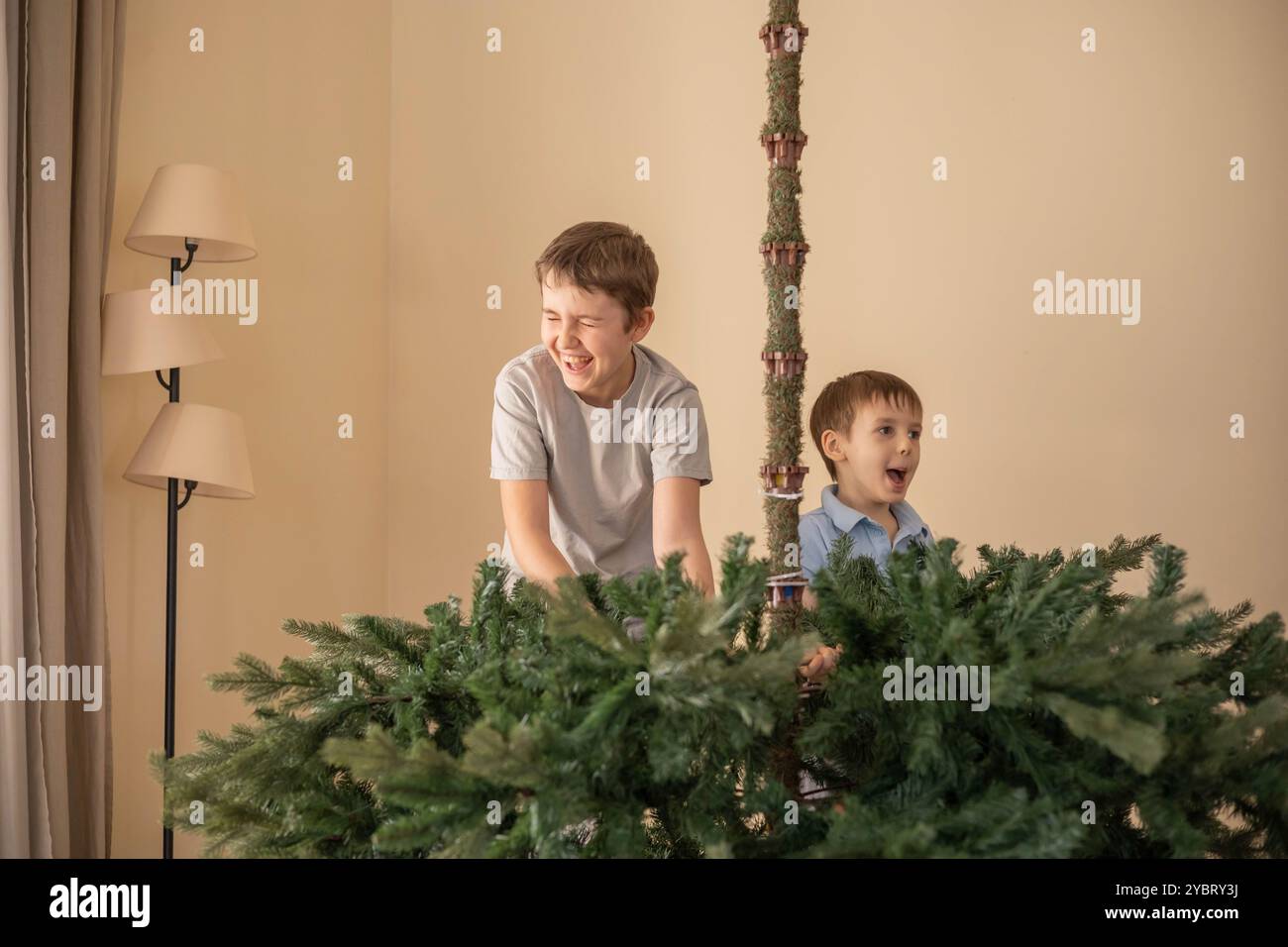 Happy children assembling an artificial Christmas tree at home in the ...