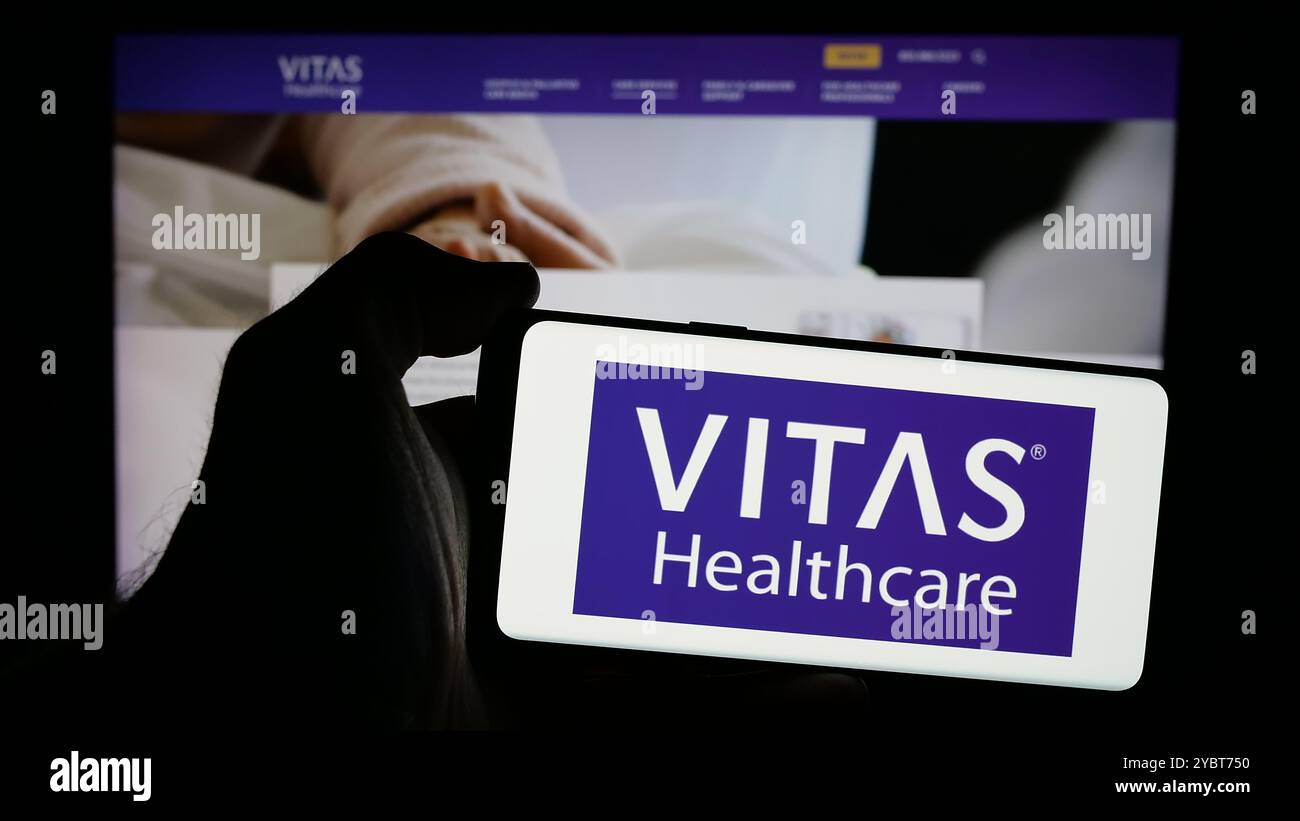 Person holding mobile phone with logo of American health care company ...