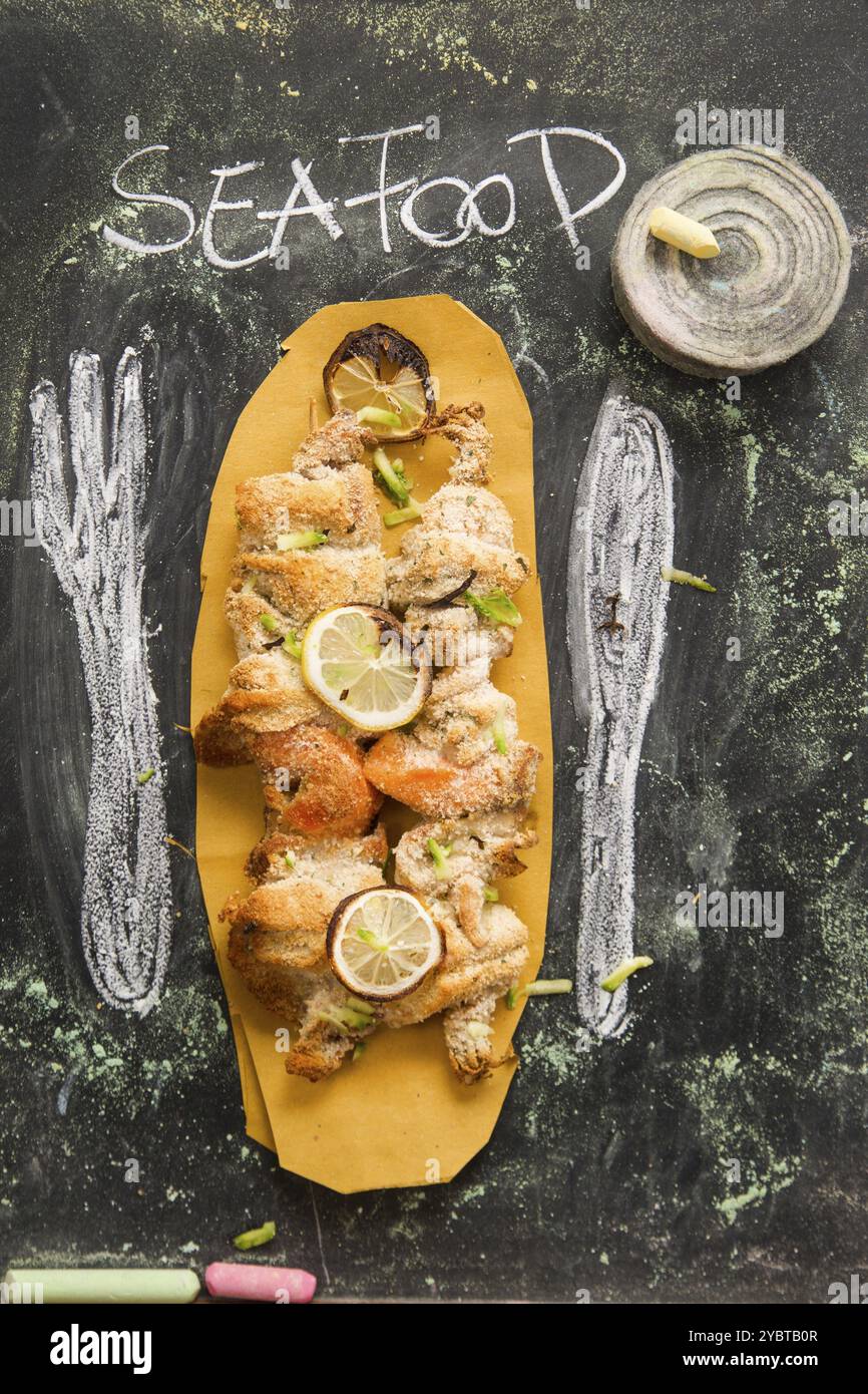 Presentation of fish skewer au gratin on chalkboard background Stock ...