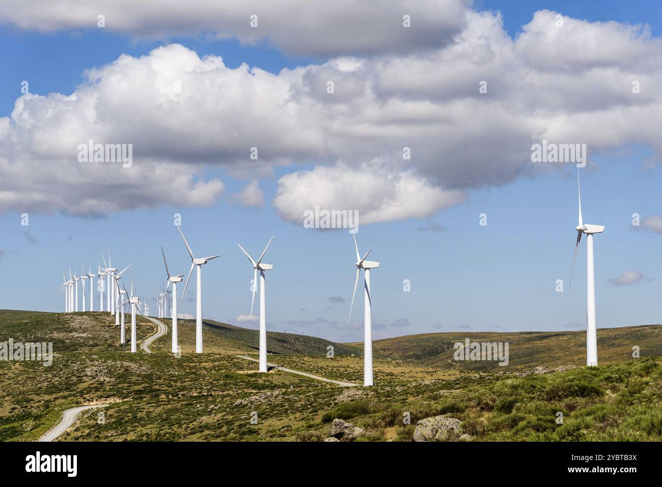 Wind turbines generating electricity on hill against blue sky with ...