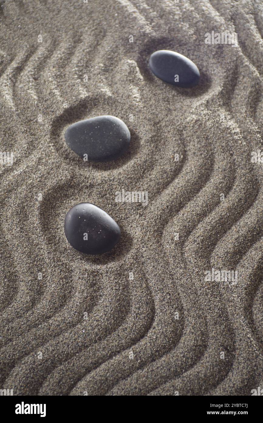 Drawings on light gray sand and black stones in a small Zen garden ...