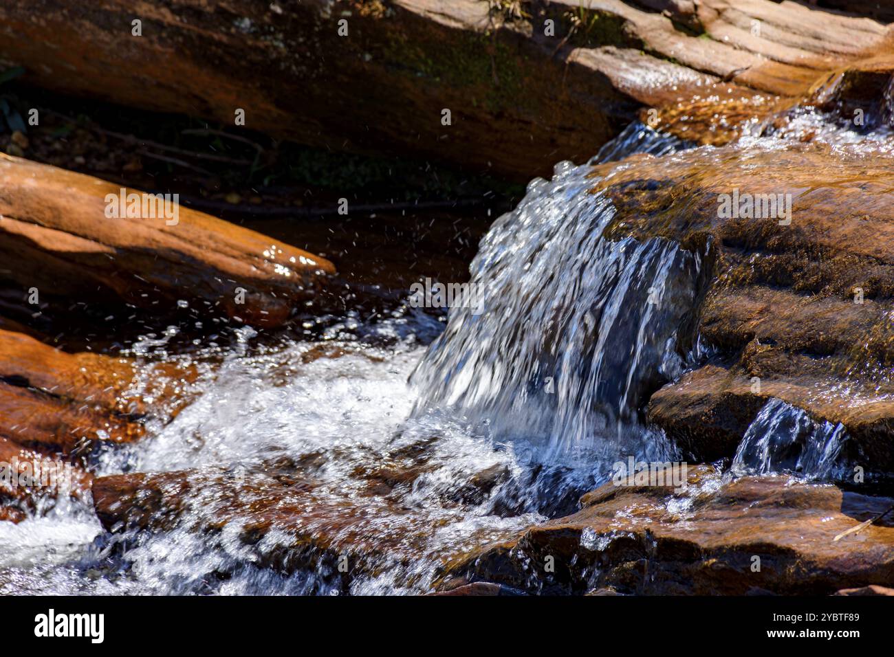 Water flowing over the rocks forming a small waterfall of clear ...