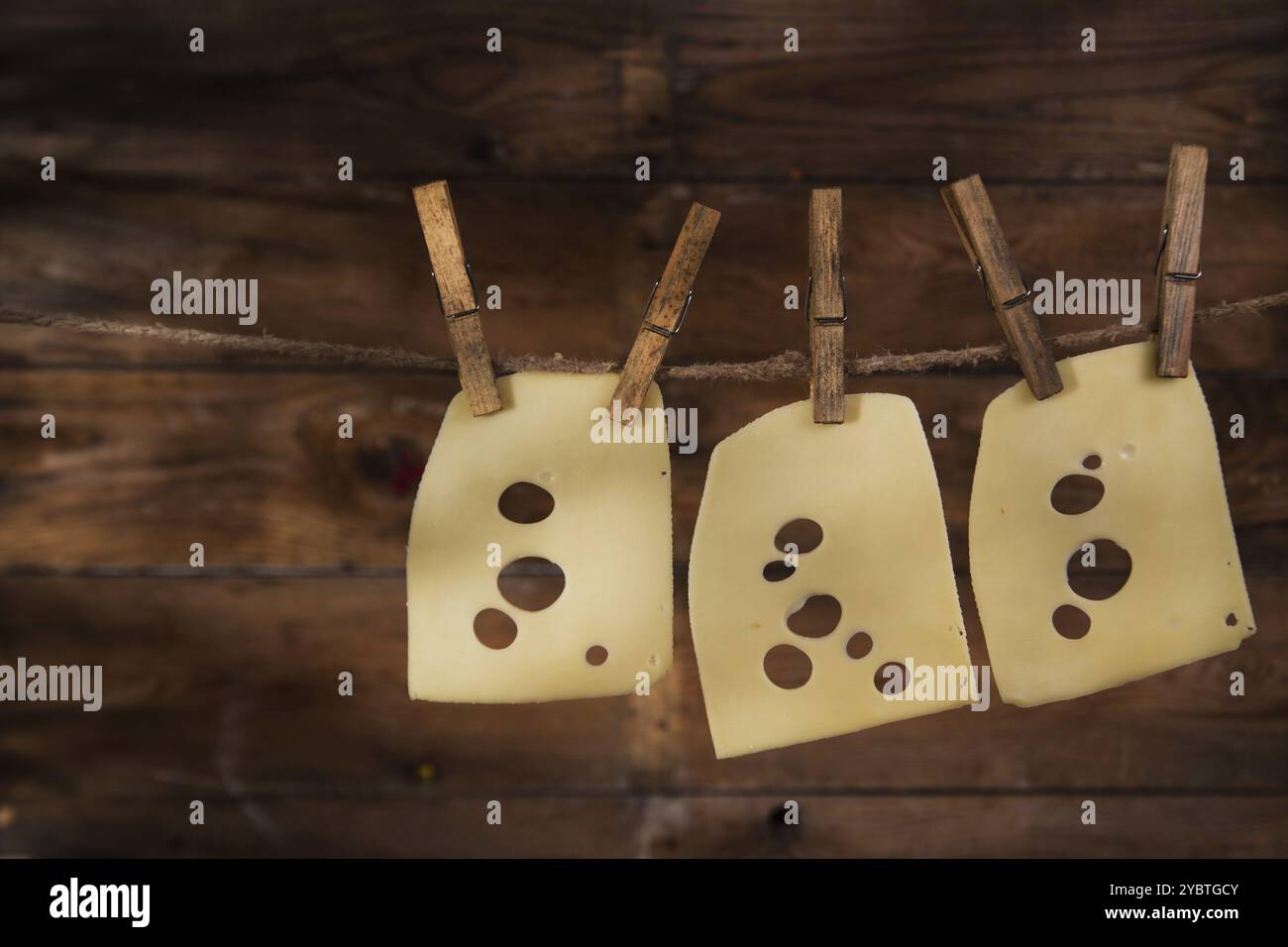 Presentation of slices of Swiss cheese Emmentaler hanging by a thread ...