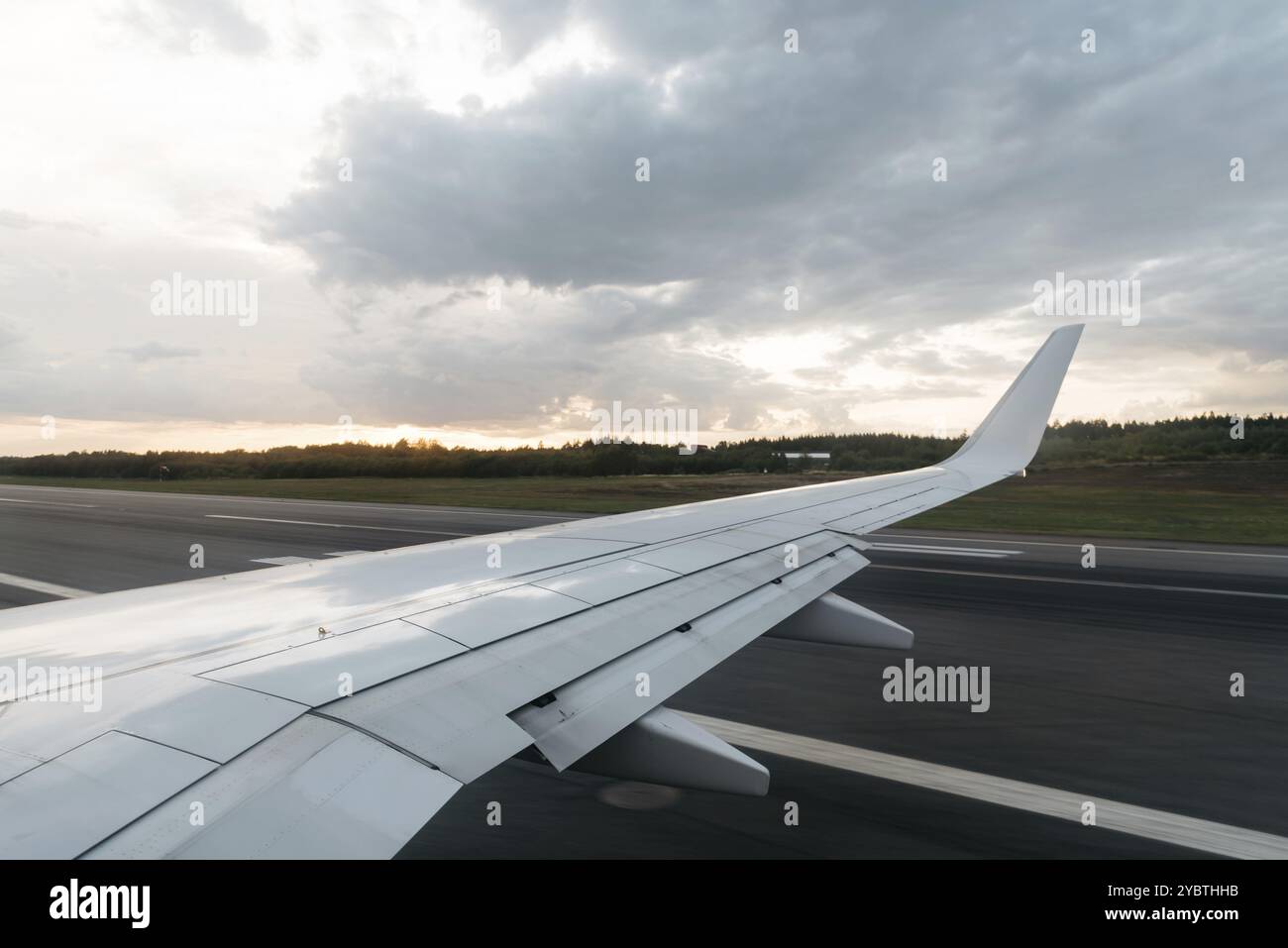 Wing of a flying airplane landing on runway, view from the airplane ...