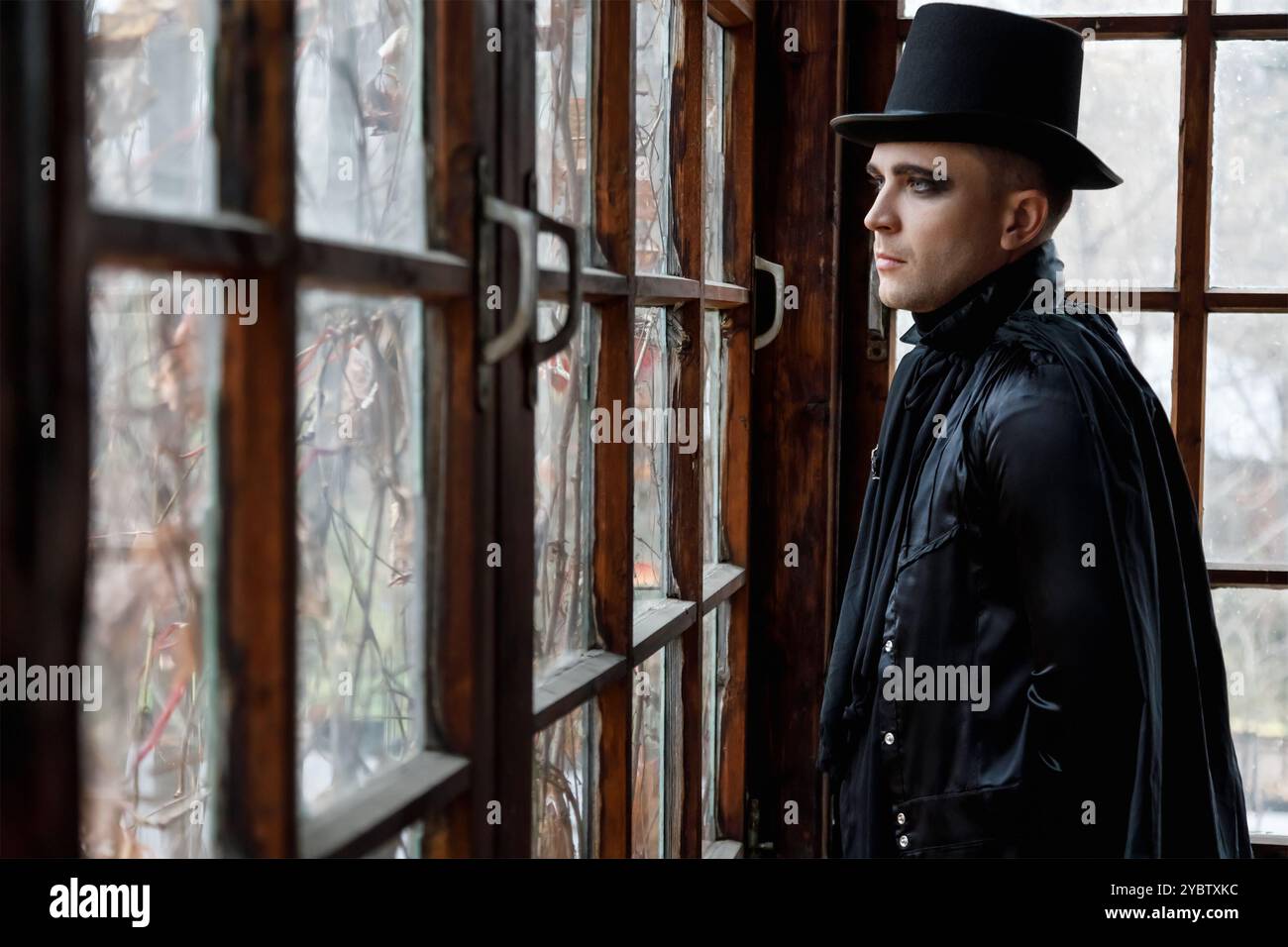 Portrait of a young handsome man in old fashioned vampire style clothes ...