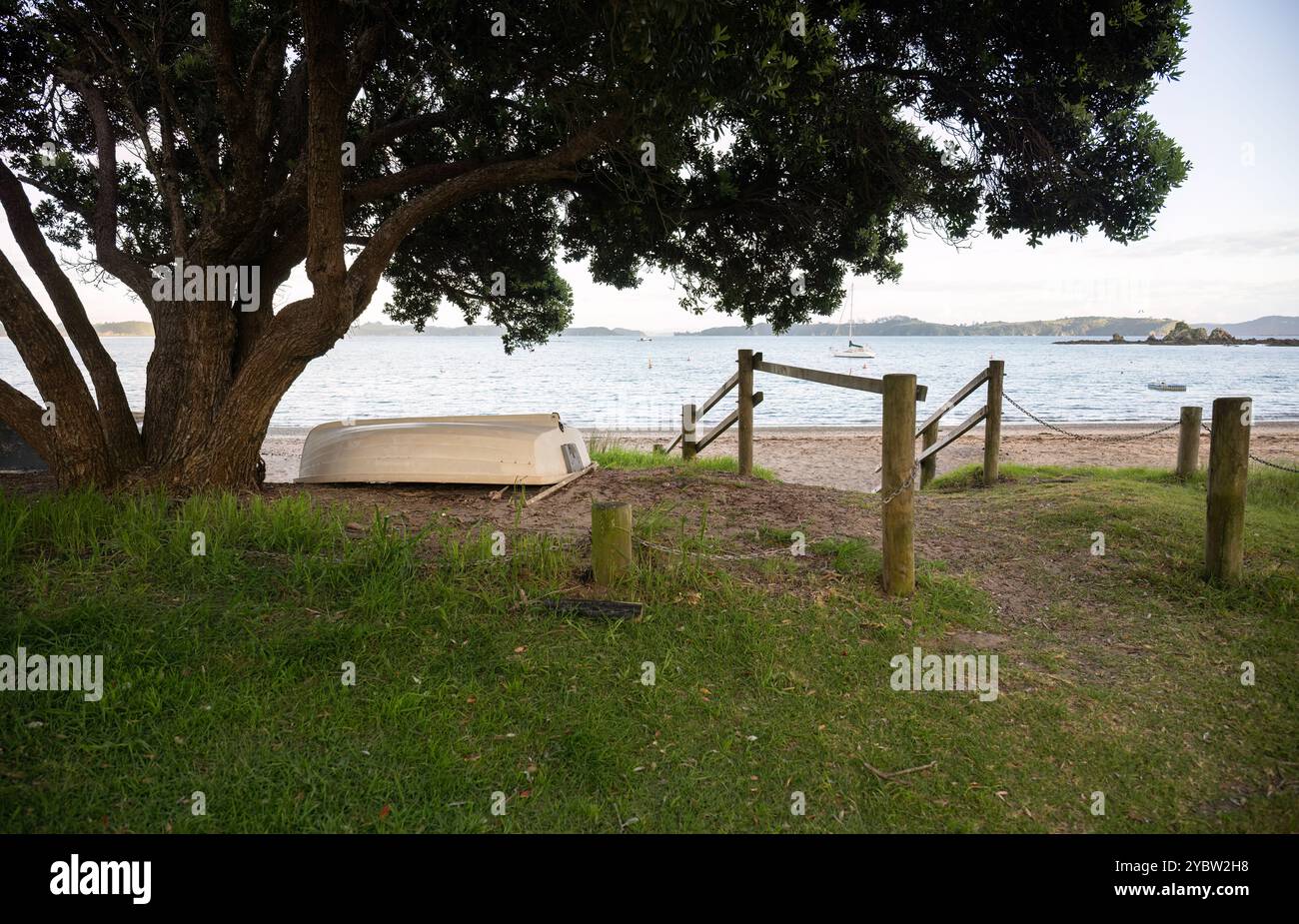 Boat under the giant Pohutukawa tree. Tapeka Point beach. Russell. Bay ...