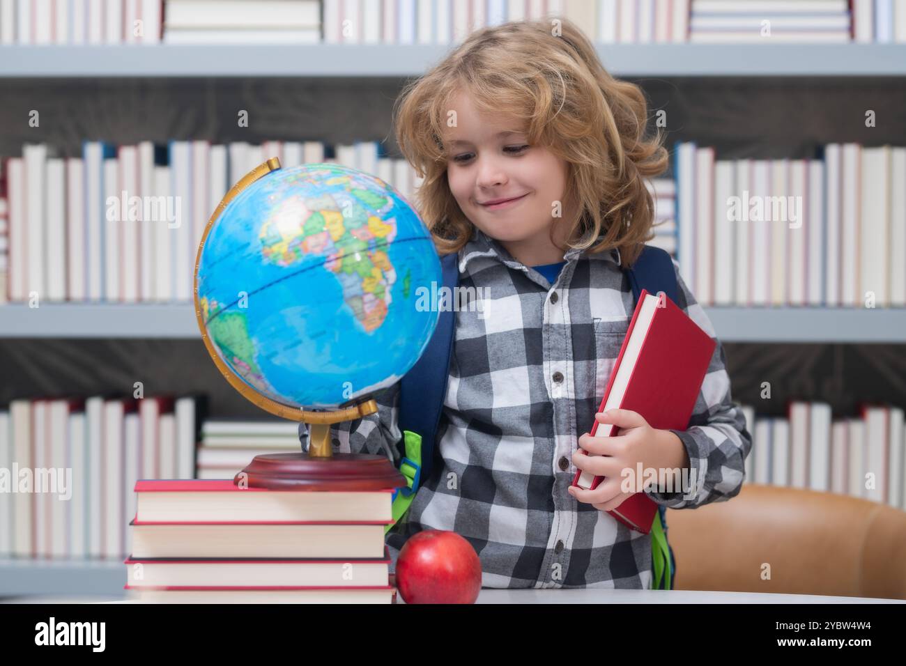 School boy looking at globe in library, geography lesson. School child ...