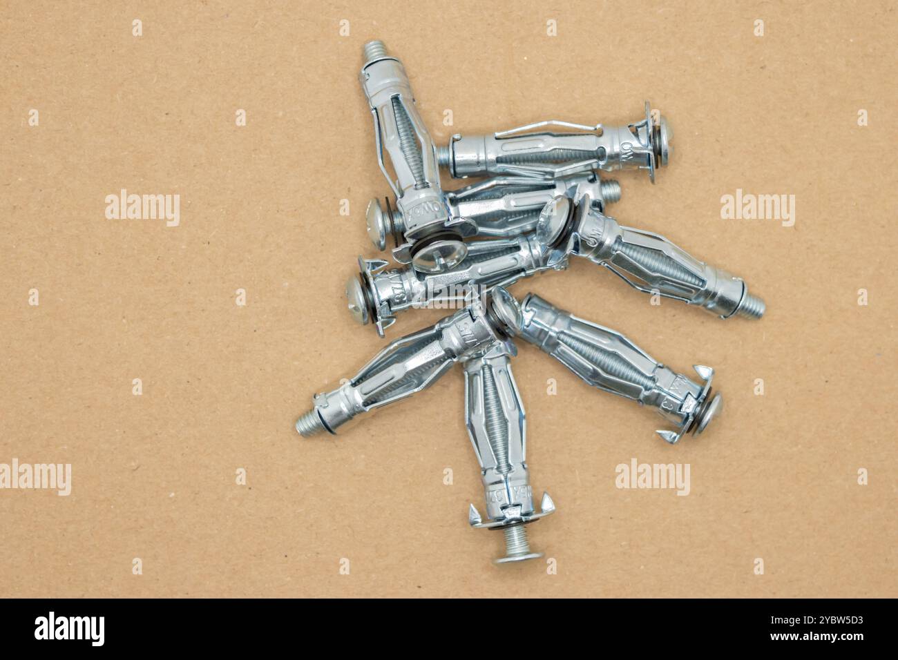 Several new shiny molly bolts are lying on a brown surface Stock Photo ...