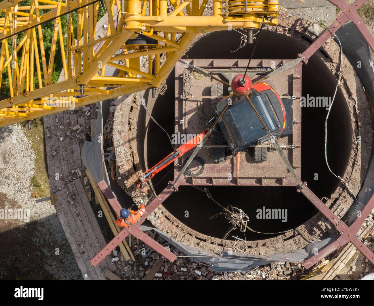 Work on top of the chimney. A suspended excavator on a crane destroys a ...